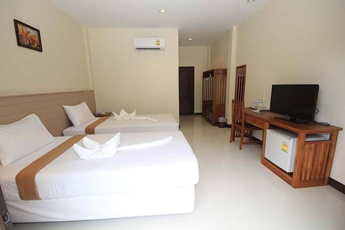 Quarto de hotel com duas camas, uma secretária e uma televisão, além de um ar condicionado.