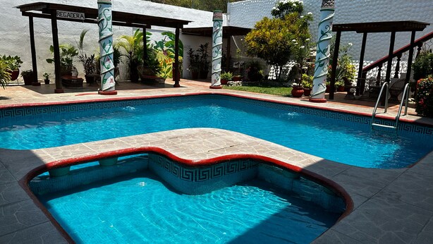 Piscina com padrão geométrico de azulejos e borda vermelha.