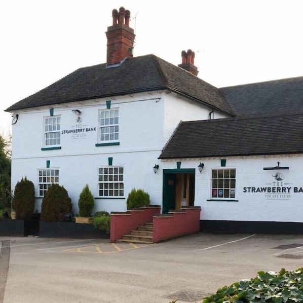 Um edifício branco com uma placa que diz 'Strawberry Bank Pub and Dining'.