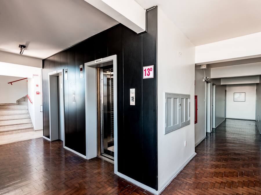 Um corredor moderno com piso de madeira, escada e elevador.