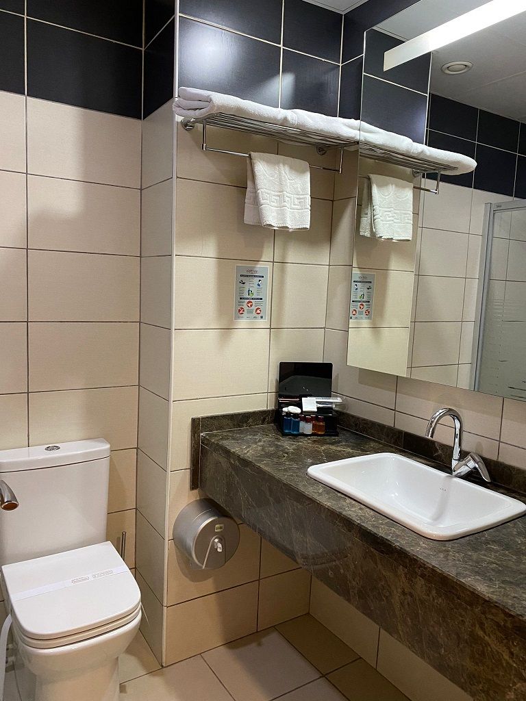 Uma casa de banho moderna com sanita, lavatório e porta-toalhas.