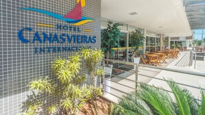 Exterior de hotel com fachada em azulejos, área de estar ao ar livre e vasos de plantas.