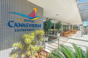 Exterior de hotel com fachada em azulejos, área de estar ao ar livre e vasos de plantas.