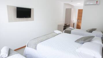 Quarto de hotel com duas camas, uma televisão de tela plana fixada na parede, um guarda-roupa de madeira e um ar condicionado embutido.