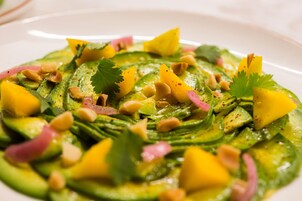 Um prato com legumes fatiados, frutos secos e ervas.