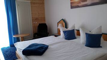 Cama bem arrumada com travesseiros brancos e azuis, um cobertor azul e cabeceira de madeira.