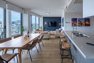 Um espaço de estar moderno com área de jantar, cozinha e janelas amplas com vista para a cidade.
