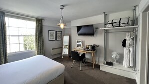 Quarto de hotel com cama, escrivaninha, cadeira, televisão e closet espaçoso.