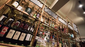 Um bar com várias prateleiras de garrafas e copos, incluindo vinho e destilados.
