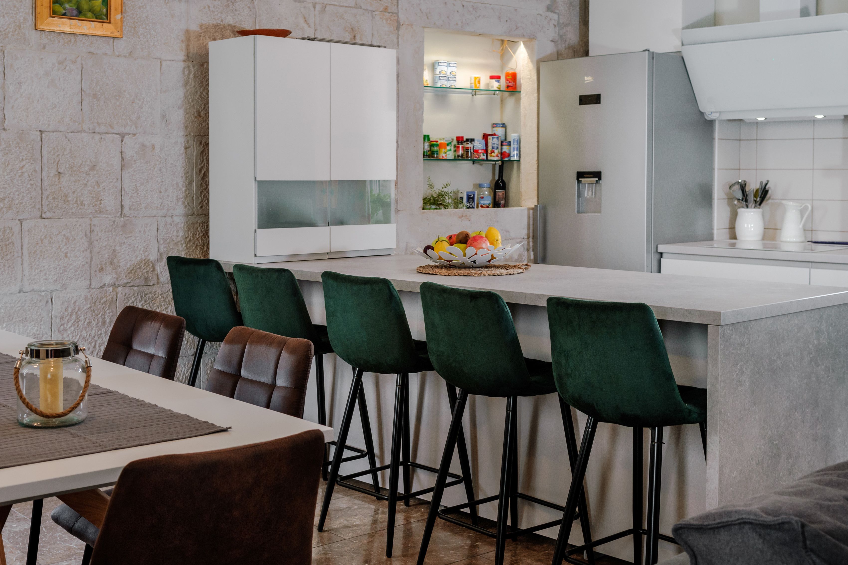 Uma cozinha moderna com ilha central, banquetas de bar e mesa de jantar.