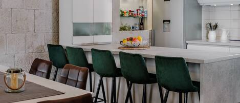 Uma cozinha moderna com ilha central, banquetas de bar e mesa de jantar.