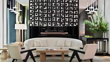 Uma sala de estar moderna com um sofá branco, duas poltronas, uma mesa de centro e um painel decorativo na parede.