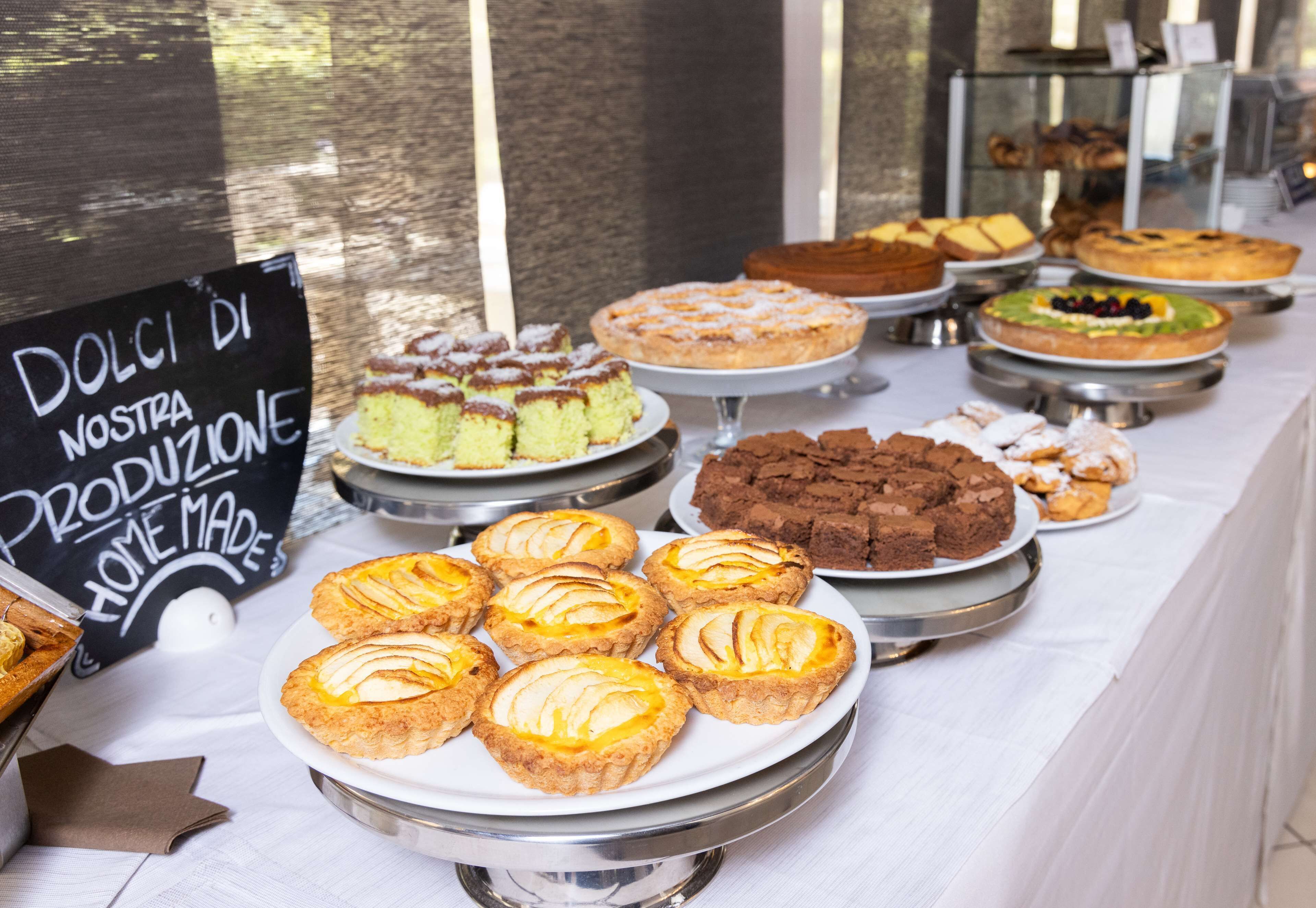 Mesa de buffet com diversos doces e um aviso indicando produção caseira.