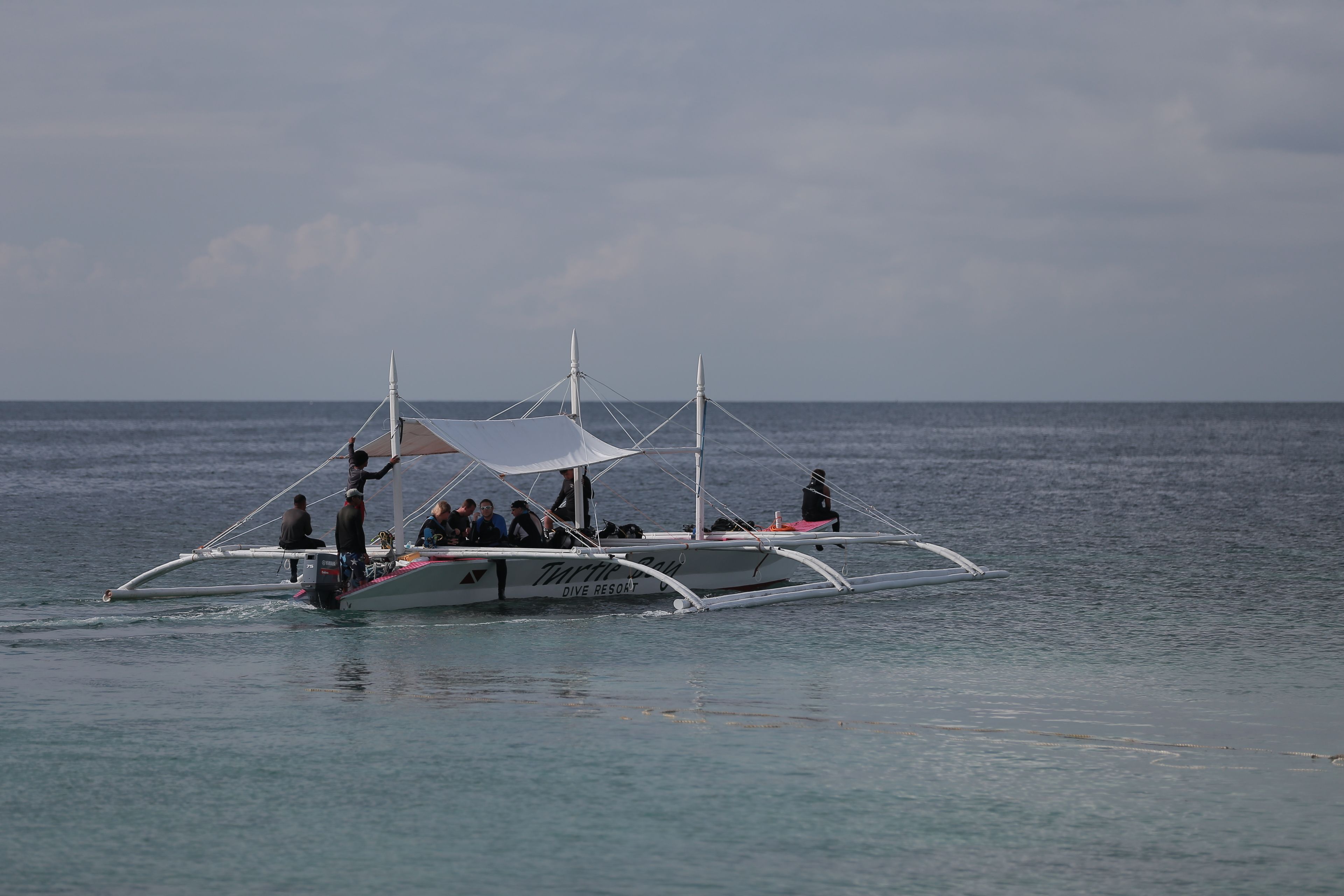 Um barco com toldo e pessoas a bordo, identificado como "Turtle Dive Resort".