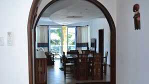 Visão do interior de uma sala de jantar com móveis de madeira e vista para o exterior.