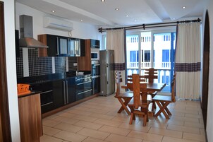 Uma cozinha moderna com armários pretos, eletrodomésticos de aço inoxidável e uma área de refeições com móveis de madeira.