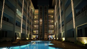 Pátio de hotel com piscina, várias varandas e luzes de Natal.