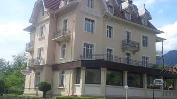 Um hotel grande, de vários andares, com arquitetura europeia clássica, com várias varandas e uma área de entrada coberta.