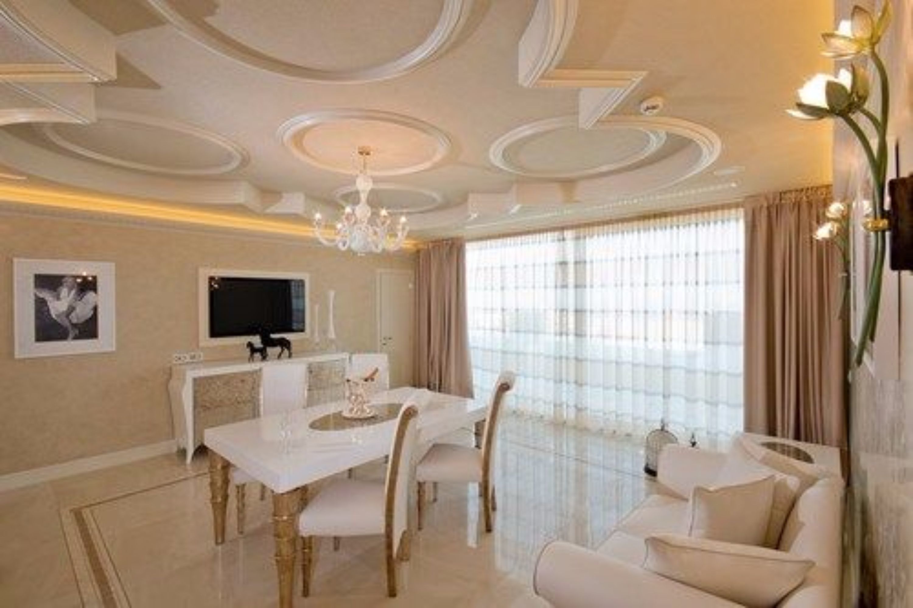 Uma sala de estar espaçosa com um sofá branco, uma mesa de jantar com cadeiras e um candelabro.