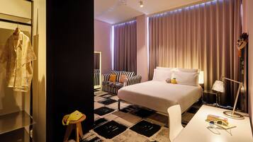 Quarto de hotel com cama, escrivaninha, cadeira, sofá e guarda-roupa.