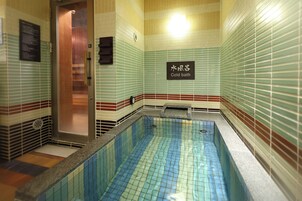 Uma pequena piscina interior com paredes azulejadas e um aviso a indicar zona de banho frio.