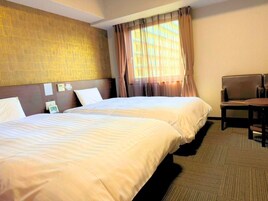 Quarto de hotel com duas camas, uma escrivaninha e uma cadeira.