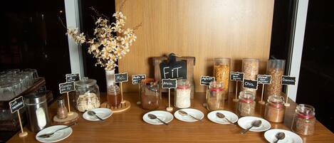 Exposição de alimentos com diversos potes identificados com ingredientes como 'Biscoff', 'Mel' e 'Chia'.
