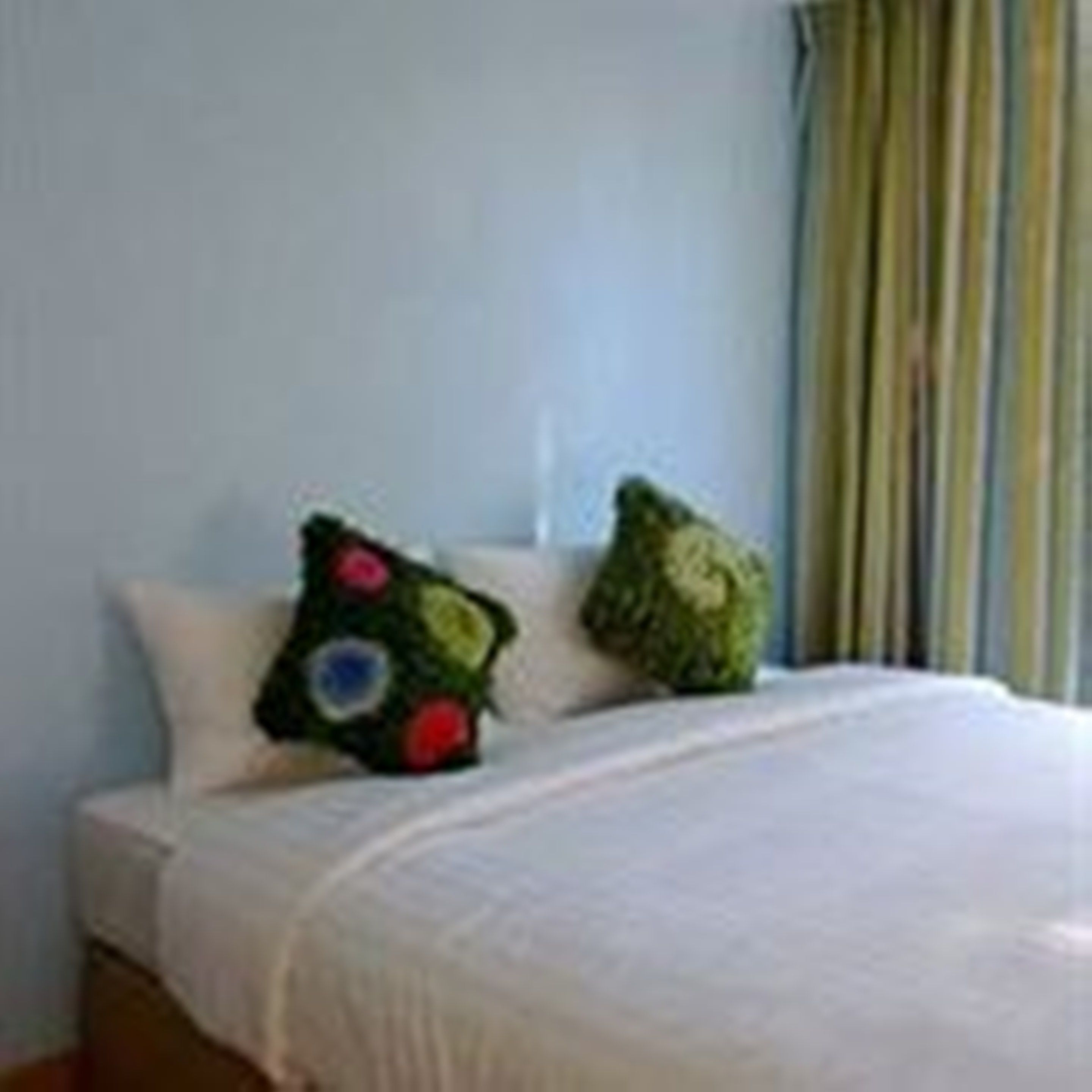 Uma cama com roupa de cama branca e dois travesseiros decorativos.