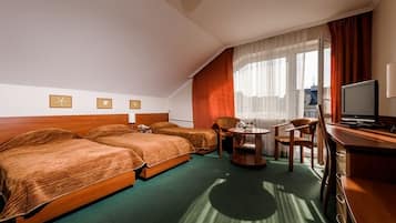 Quarto de hotel com duas camas, uma escrivaninha, uma cadeira, uma televisão e uma pequena mesa.