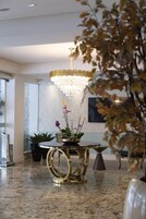 Um lobby moderno com uma mesa redonda, um candelabro e plantas em vasos.