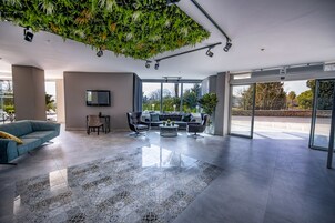 Uma sala de estar espaçosa com design moderno, com um amplo conjunto de sofás, uma mesa de centro e um tapete estampado.