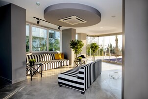 Um interior moderno com um sofá listrado, um banco comprido e uma pequena mesa com plantas.