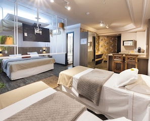 Quarto de hotel com duas camas, uma escrivaninha, televisão e banheiro.