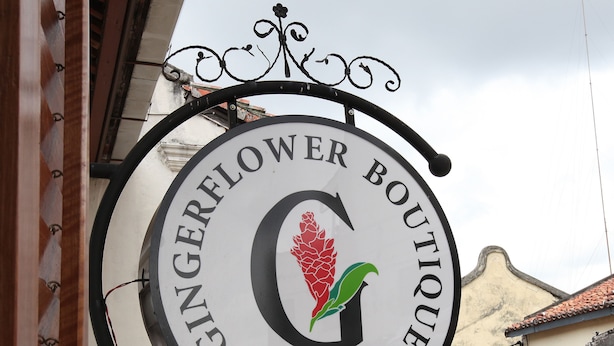 Um sinal circular com o texto "GINGERFLOWER BOUTIQUE HOTEL" e um logotipo com uma flor vermelha e folhas verdes.