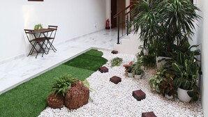 Um pátio com área de refeições, escadaria e plantas em vasos.