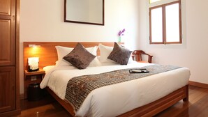 Quarto com cama de madeira, mesa de cabeceira, espelho e janela.