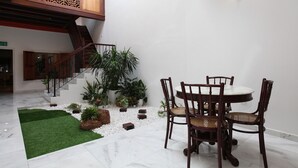 Uma área de refeições com uma mesa redonda e cadeiras, uma escada e plantas em vasos.