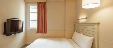 Quarto de hotel com cama, televisão, janela com cortinas e luminária pendente.