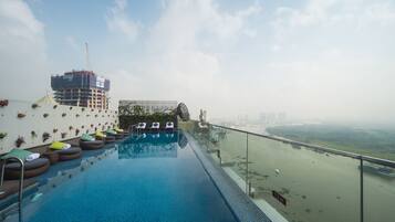 Piscina infinita no terraço, com espreguiçadeiras e vista para o horizonte da cidade.