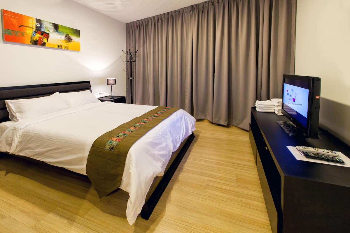 Quarto de hotel com uma cama, uma televisão e uma escrivaninha com controle remoto.