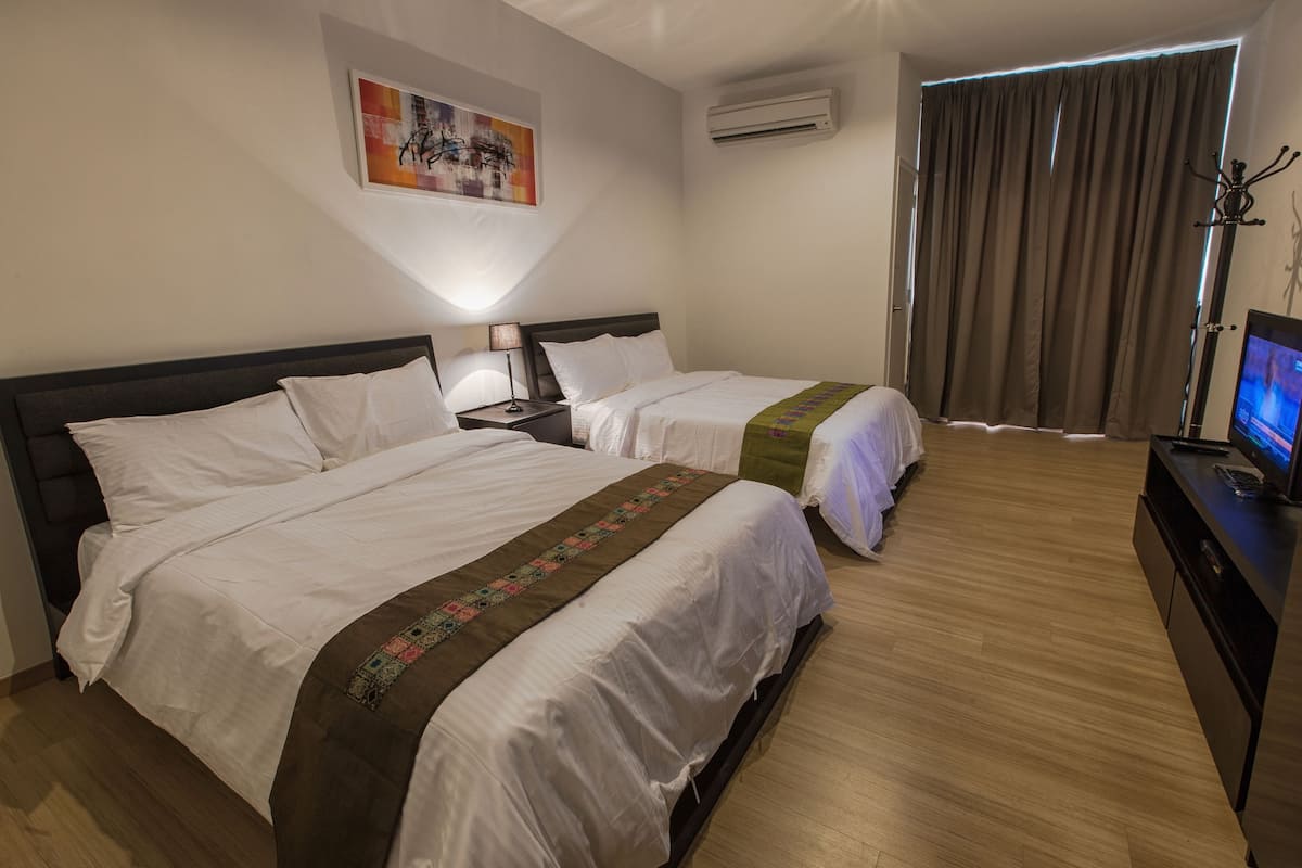 Quarto de hotel com duas camas, televisão de tela plana, escrivaninha e ar condicionado.