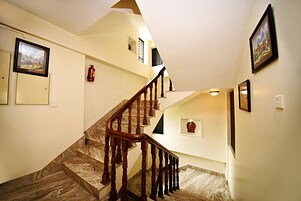 Escadaria com balaústres de madeira e degraus de mármore.