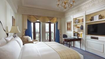 Quarto de hotel com uma cama grande, uma escrivaninha, uma televisão e uma estante de livros.