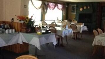 Uma área de refeições com mesas montadas, cadeiras e um buffet.