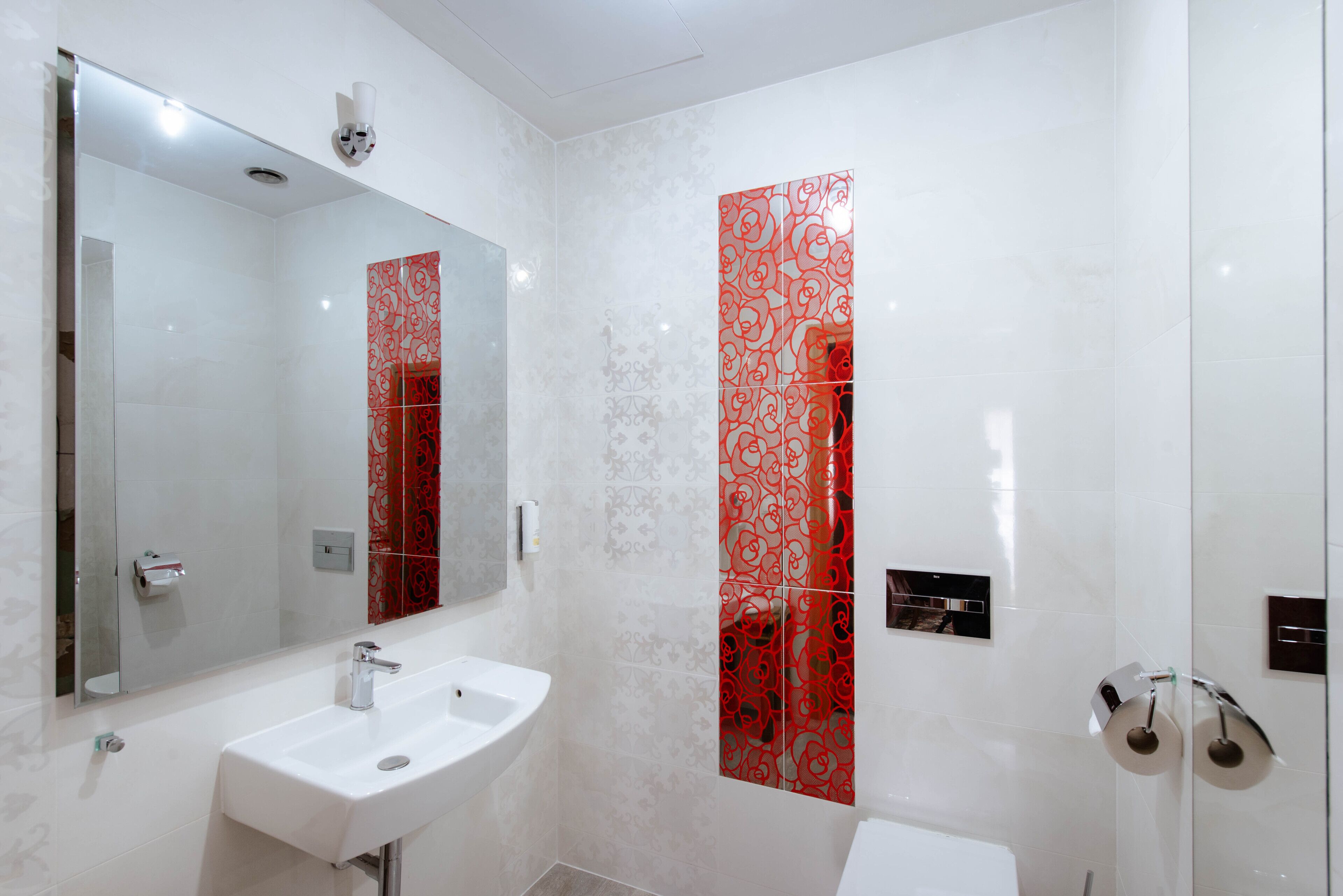 Casa de banho moderna com lavatório branco, espelho e chuveiro.