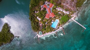 Vista aérea de uma ilha tropical com piscina, píer e cais.