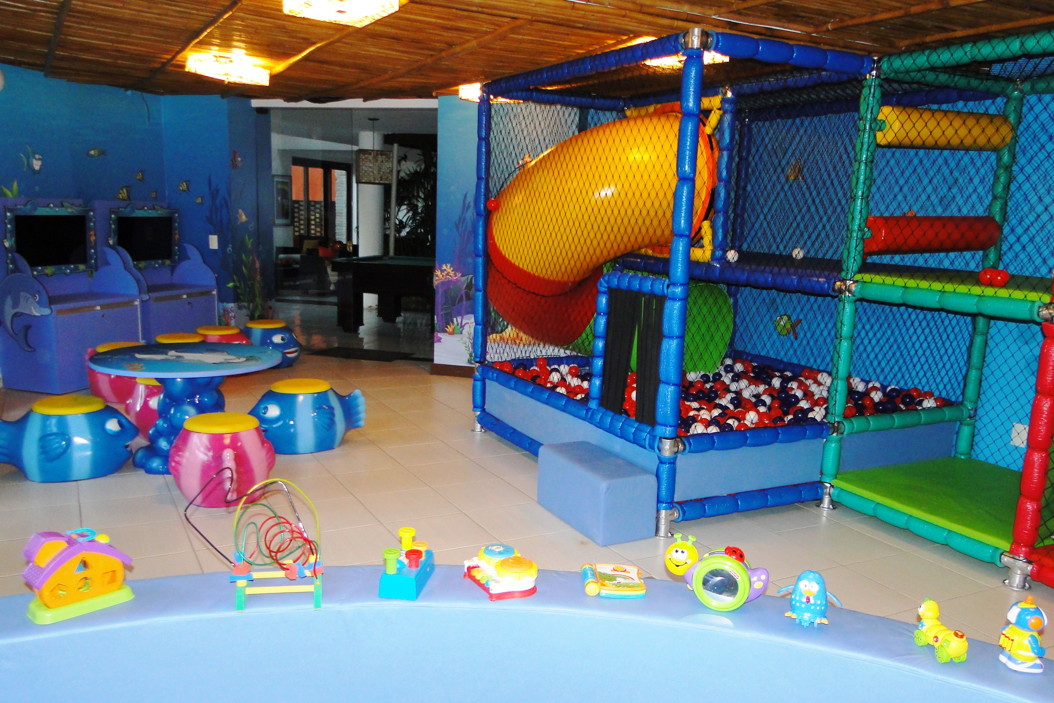 Espaço infantil com estrutura de escalada, piscina de bolinhas e diversos brinquedos.