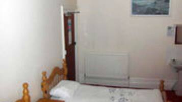 Quarto com duas camas de solteiro, cabeceira de madeira, radiador e um quadro na parede.