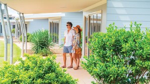 Um casal em área externa coberta, com um edifício moderno ao fundo.