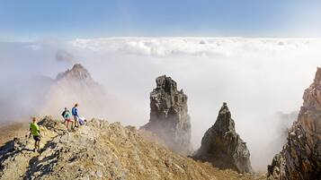 Um pico montanhoso rochoso com caminhantes no cume.